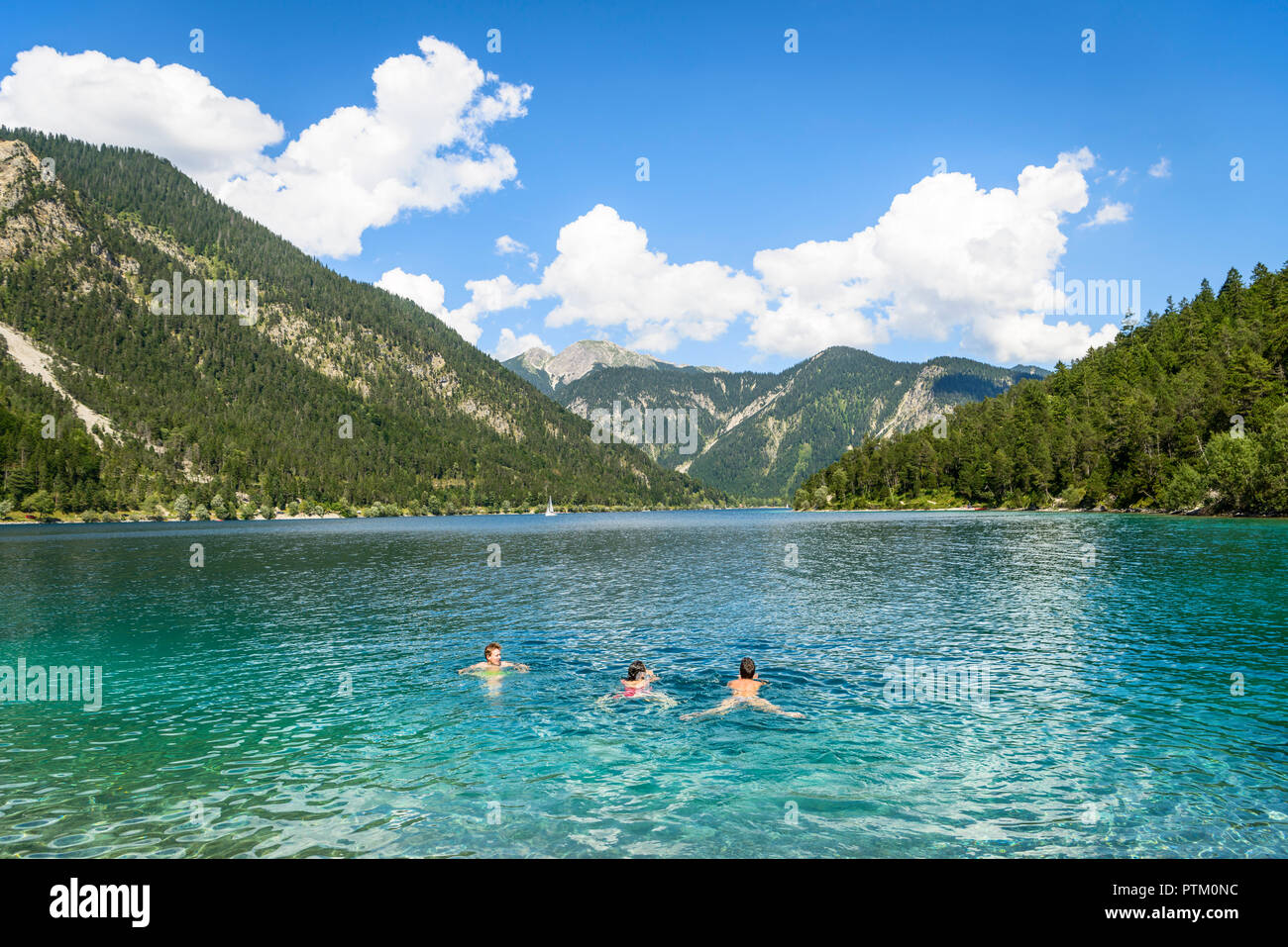 Drei Menschen baden, schwimmen im See Plansee, Ansicht vom Ufer ...