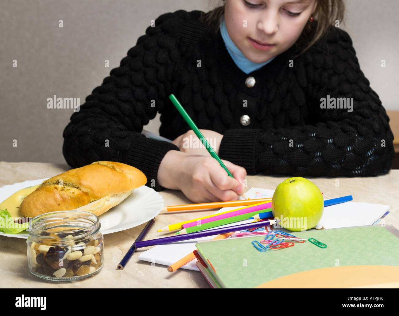 Das Mädchen hat die Lektionen, auf dem Tisch liegt ein Sandwich, Obst ...