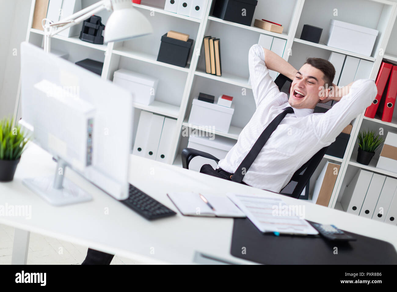 Ein junger Mann an einem Computer Schreibtisch im Büro sitzen, lehnte ...