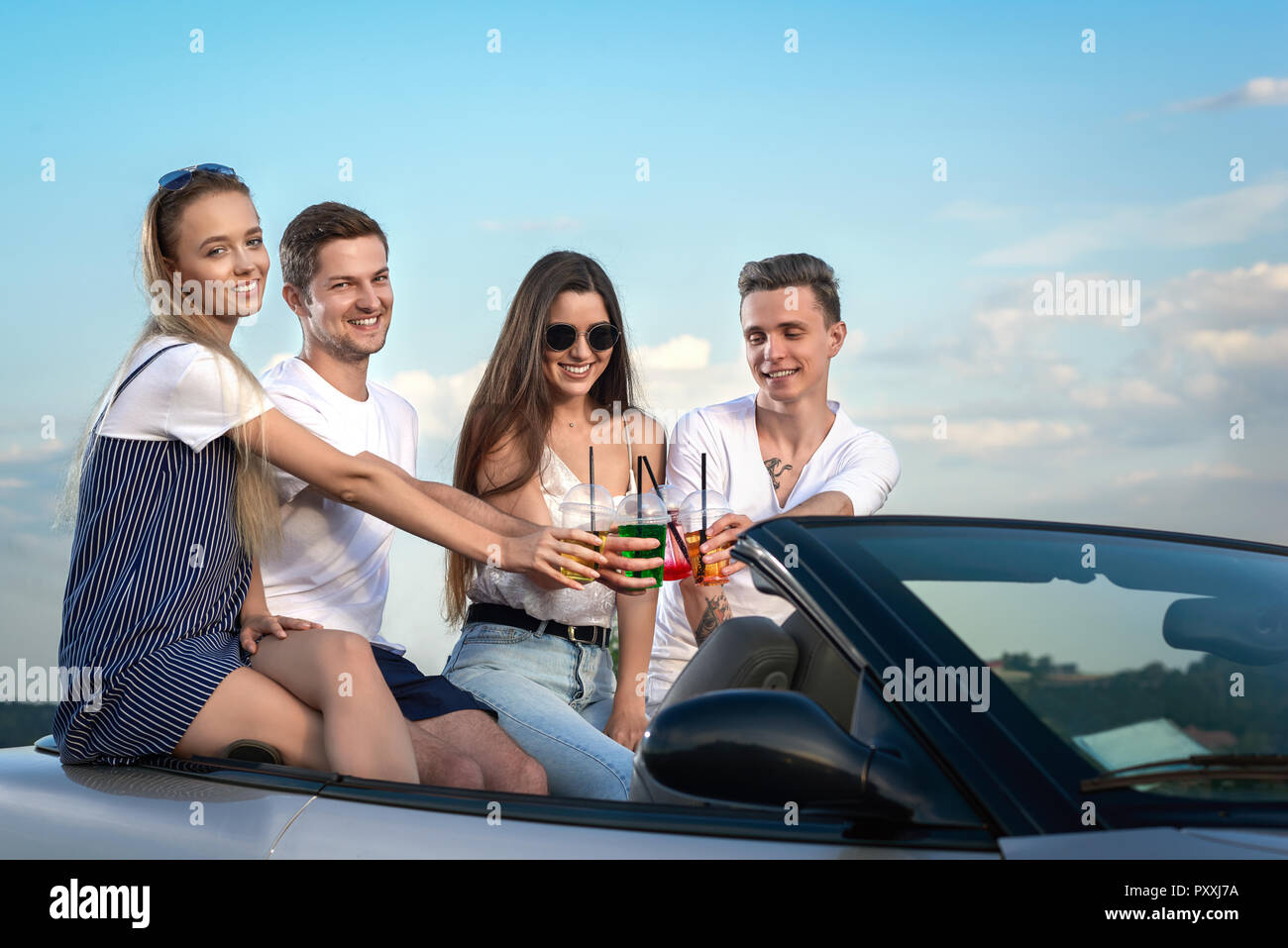 Unternehmen von vier Freunden zusammen sitzen auf Cabrio und Anstoßen ...