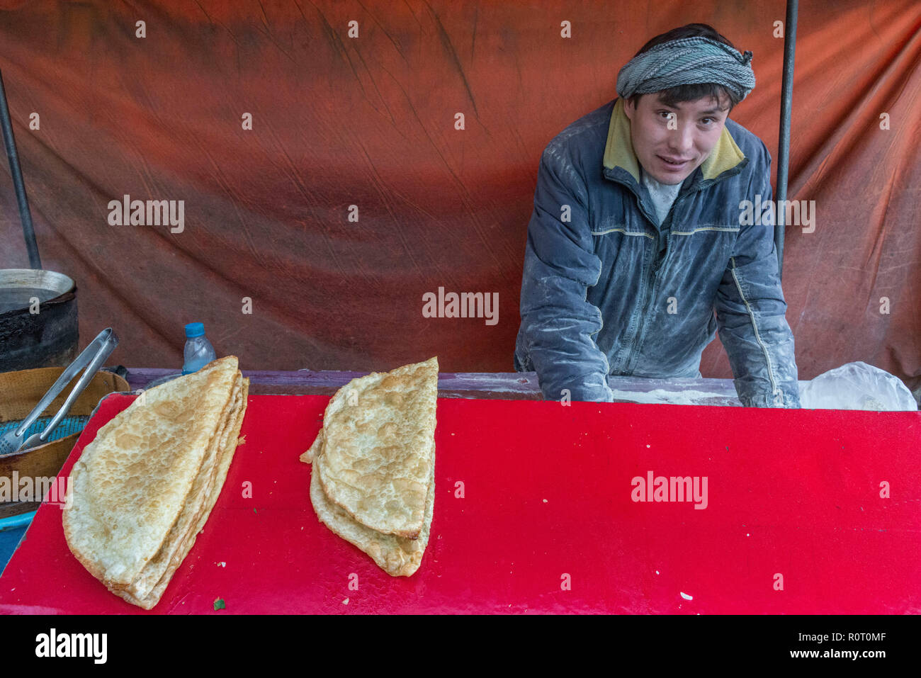 Junger Mann Brot backen und verkaufen es auf roter Tisch Im Mazar-e ...