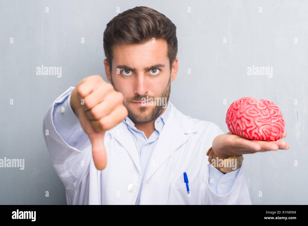 Hübscher junger Arzt Psychologe Mann über Grau grunge Wand Holding ein ... Hübscher junger Arzt Psychologe Mann über Grau grunge Wand Holding ein ...