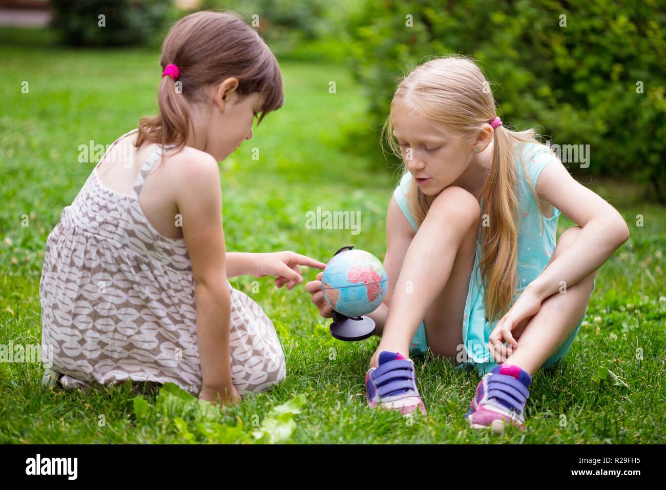 Kleine hübsche Mädchen Freundinnen sitzen auf der Wiese und Blick auf ...