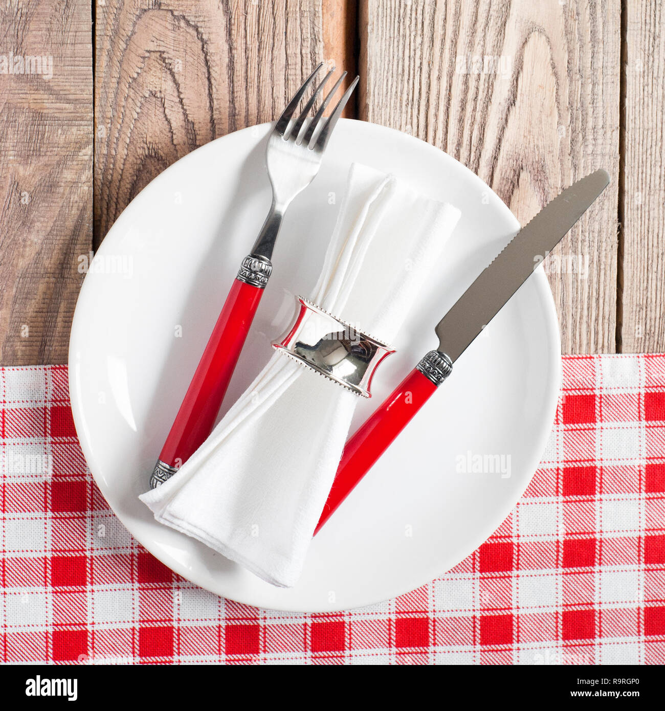 Tabelle mit einem Teller, Besteck und Servietten in roten und weißen ...