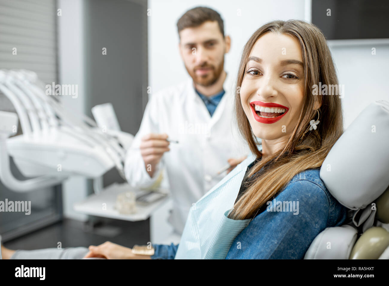 Portrait einer jungen lächelnde Frau mit gesunden Lächeln sitzt in der Zahnarztpraxis mit ...