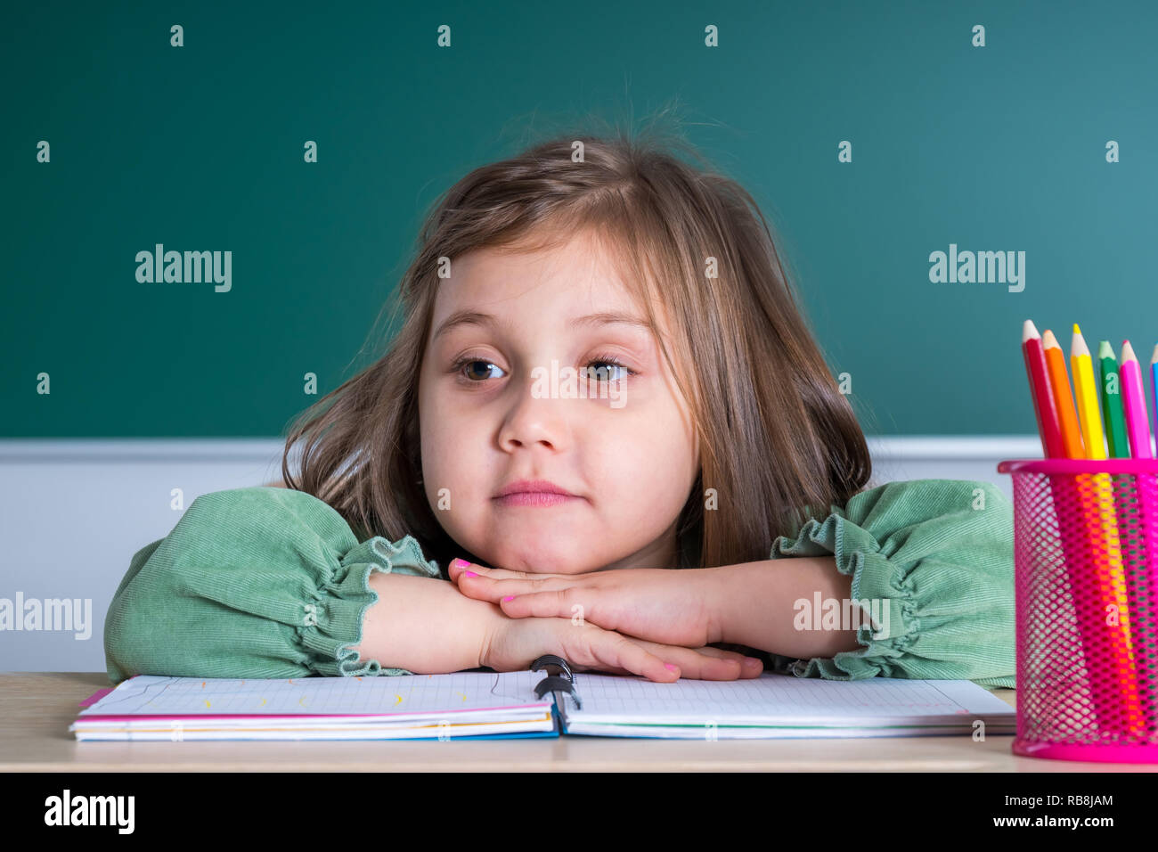 Kleine hübsche Mädchen in der Klasse sitzen am grauen Schreibtisch und ...