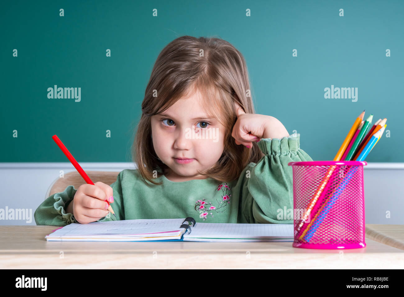 Kleine hübsche Mädchen in der Klasse sitzen am grauen Schreibtisch und ...