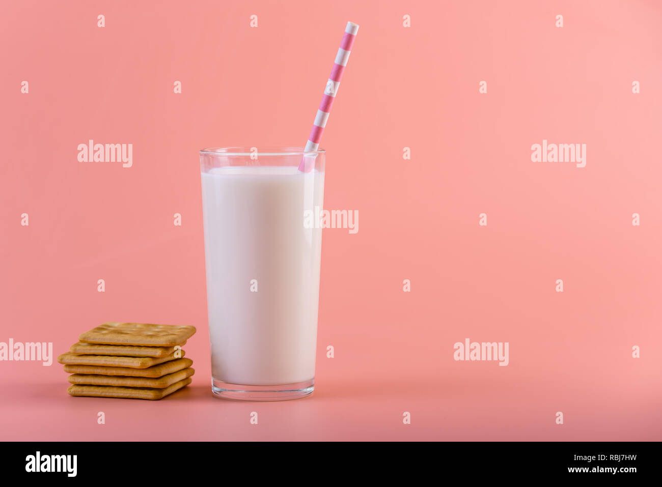 Ein Glas Frische Milch mit Strohhalm und Cookies auf einem rosa ...