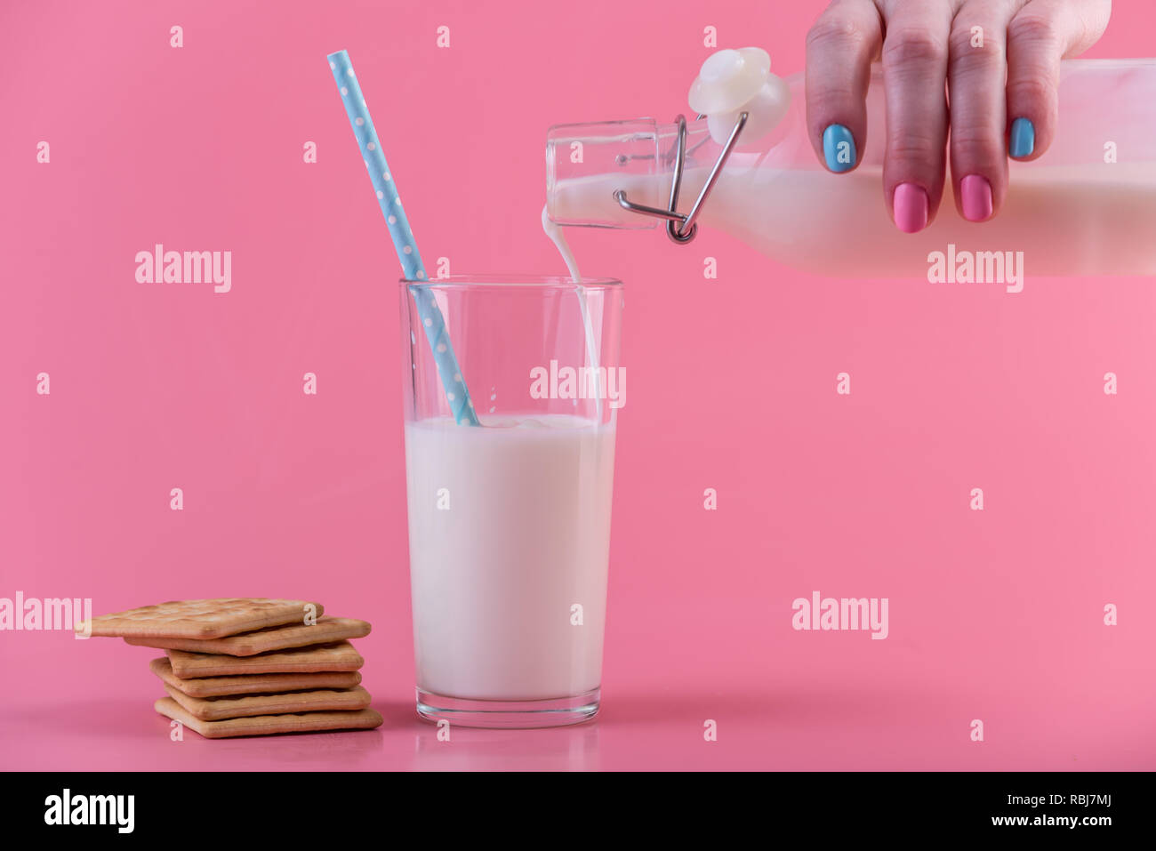 Die Hand einer Frau giesst frische Milch aus einem Glas Flasche in ein ...