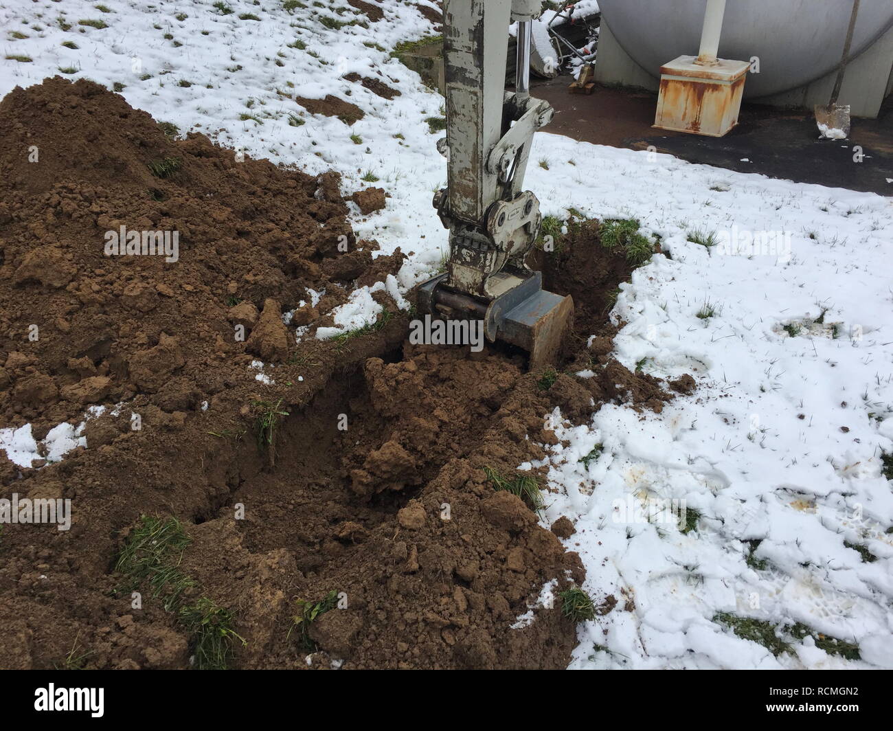Bagger Schaufel gräbt sich in den Boden bedeckt mit Schnee ...
