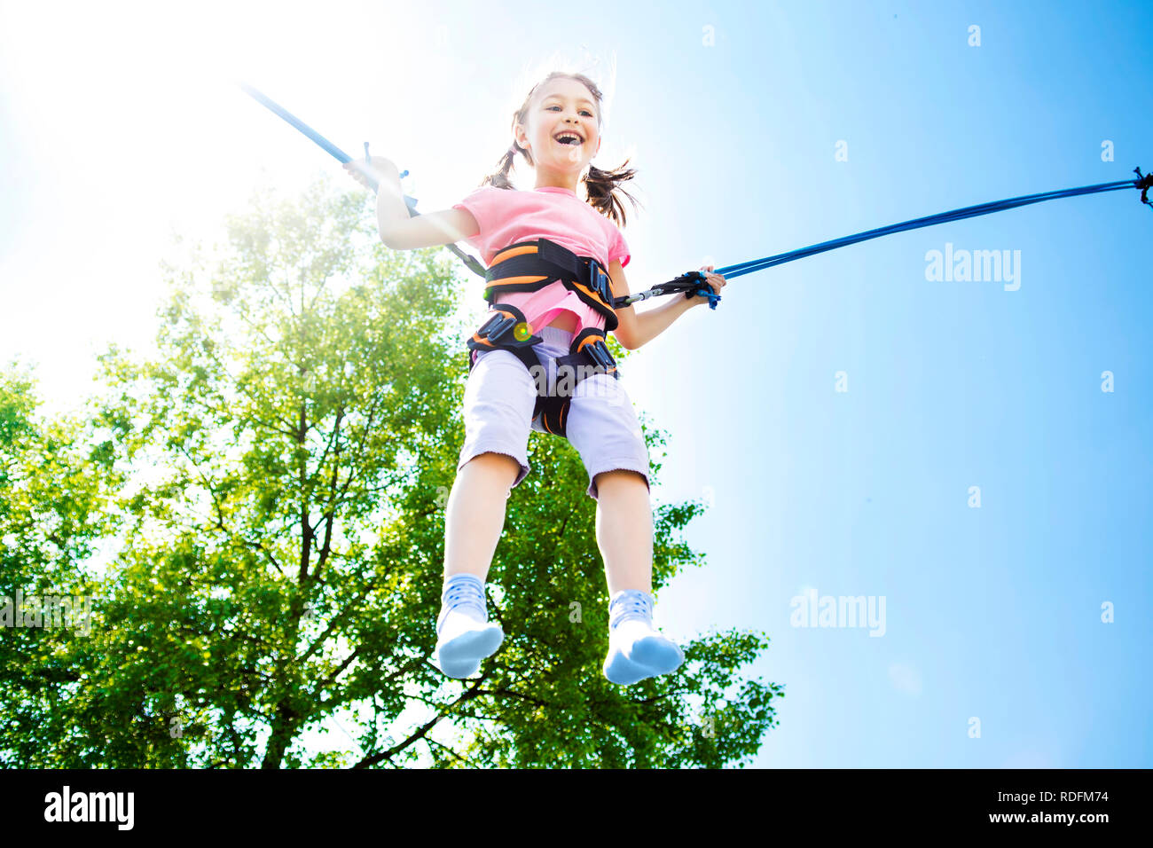 Kleines Mädchen springt hoch in die Luft mit einem Bungee Trampolin ...