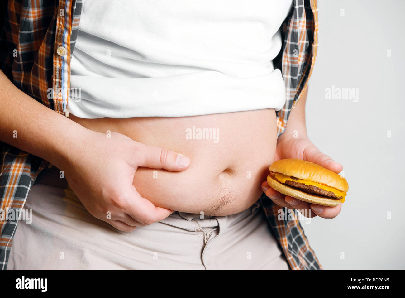 Fetter Mann mit einem Burger in der Hand, unterstützt sagging dicken ...