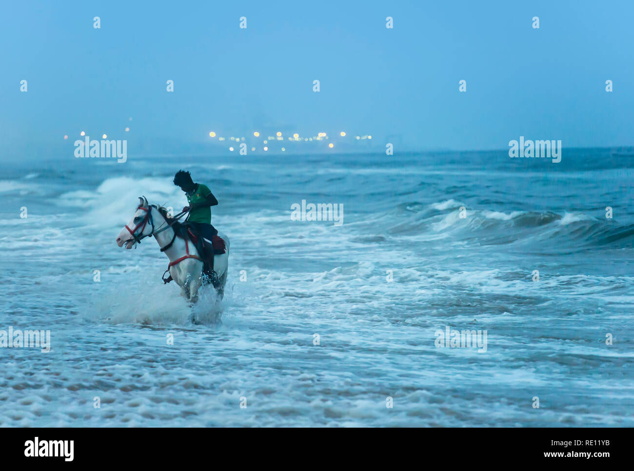 Reiten am Strand in Chennai, Indien mit den Wellen die Beine des ...