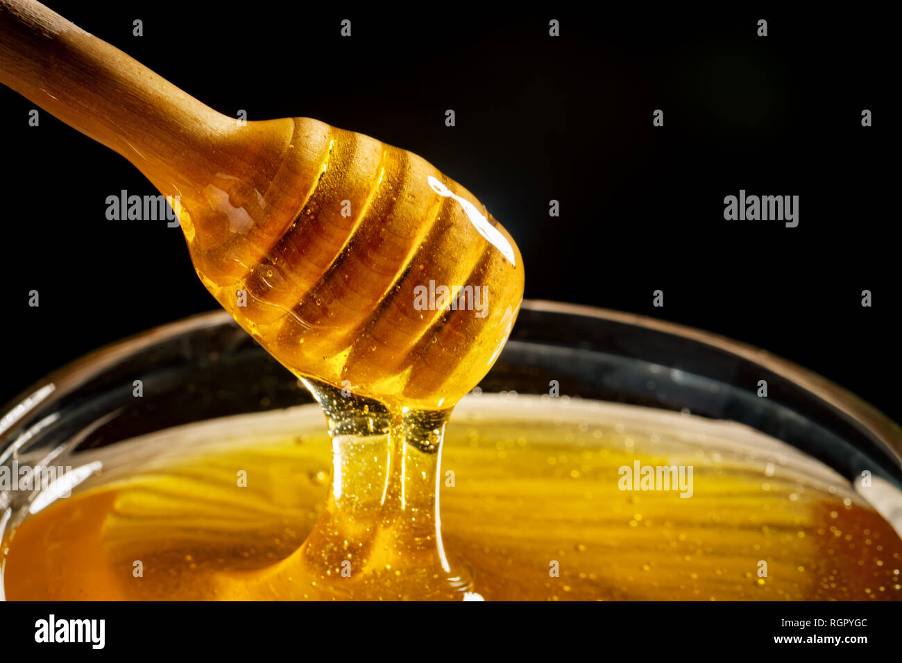 Honig mit Gold Farbe fließt unten von einem Löffel. Gesunde Ernährung ...