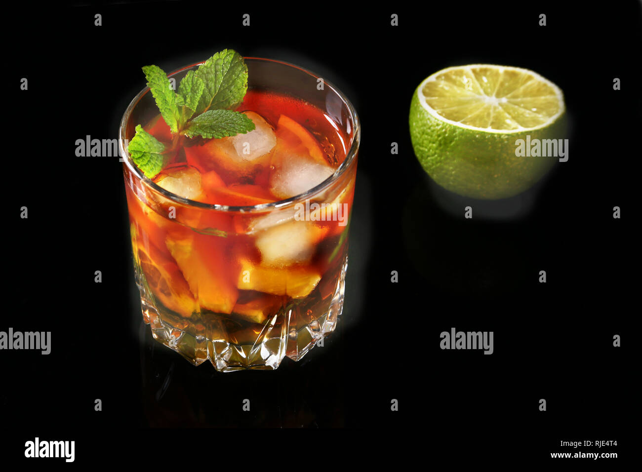 Glas dunkler Rum Cocktail mit Limone, Orange, Eiswürfel und Minze auf ...