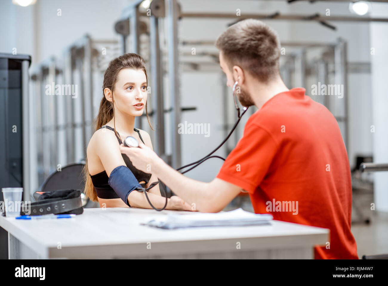 Der Mensch als rehab in roter Uniform Druckmessung mit einer jungen ...