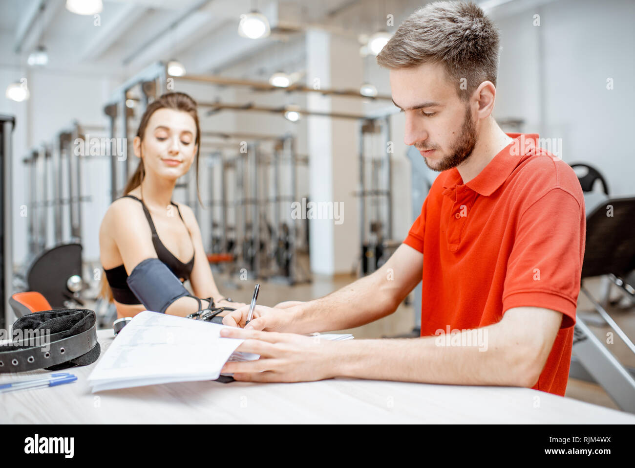 Der Mensch als rehab in roter Uniform Druckmessung mit einer jungen ...