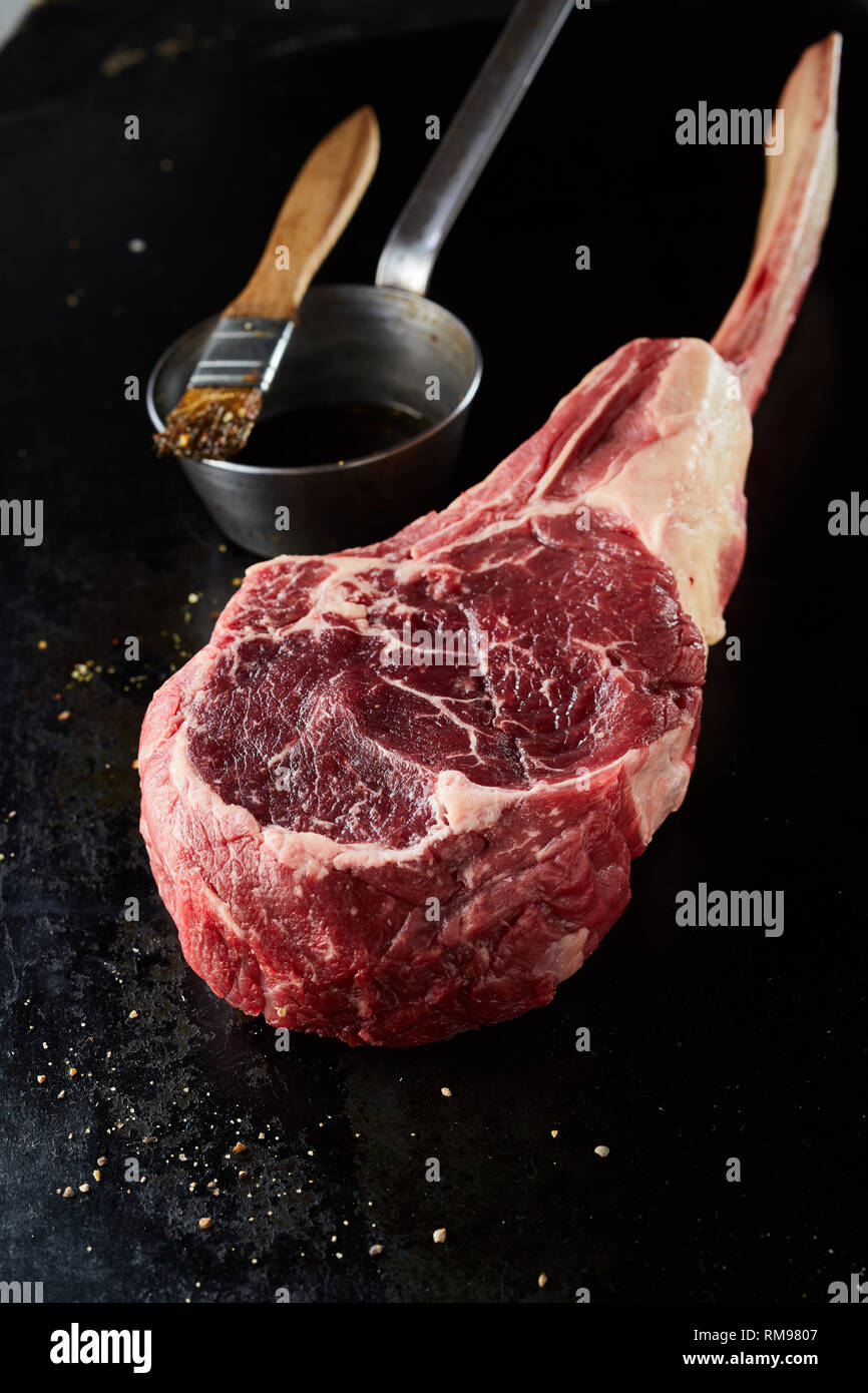 Nahaufnahme der rohen Delmonico tomahawk Steak mit Knochen auf schwarz ...