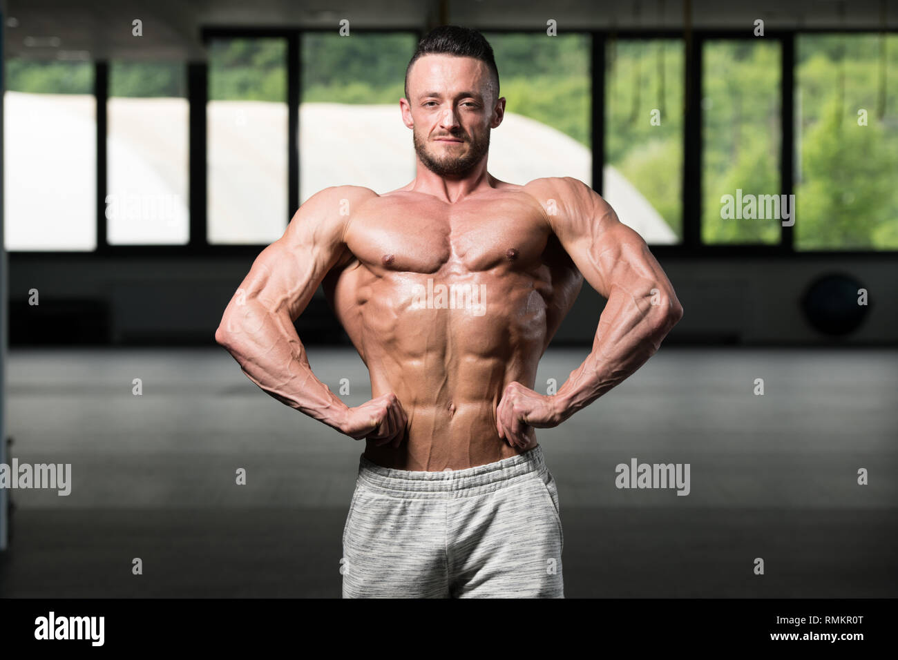 Hübscher junger Mann standhaft In der Turnhalle und biegen Muskeln ...