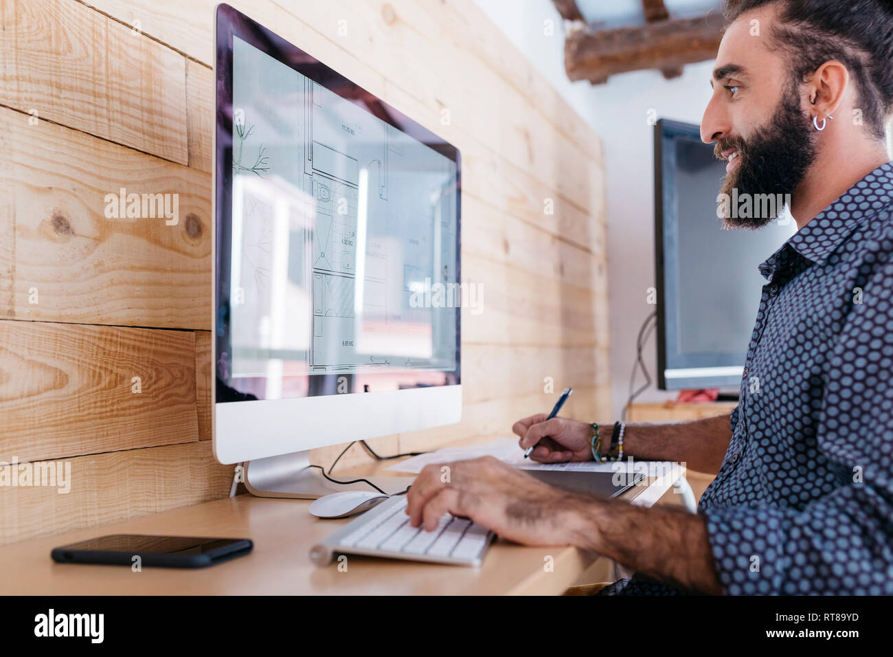 Lächelnden jungen Mann bei der Arbeit auf dem Boden Plan zu Hause mit ...