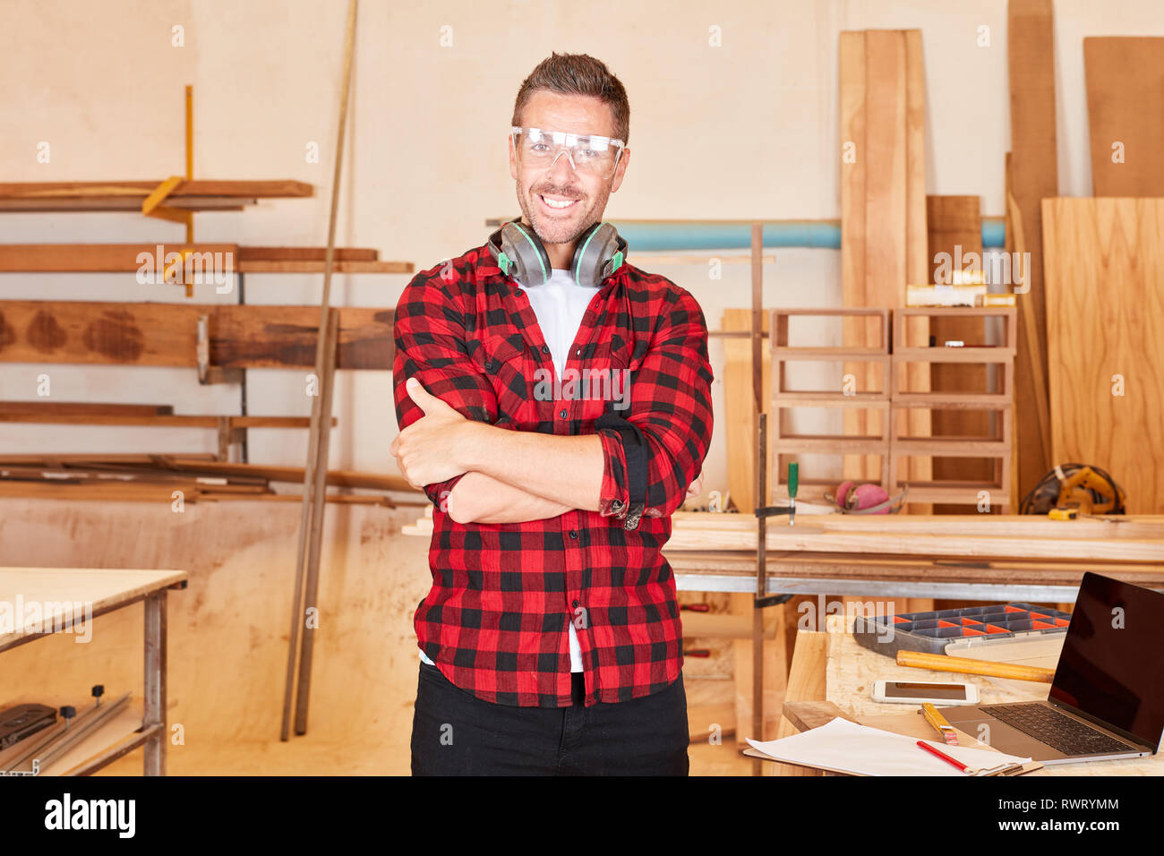 Handwerker steht selbstbewusst und stolz in der Werkstatt mit ...