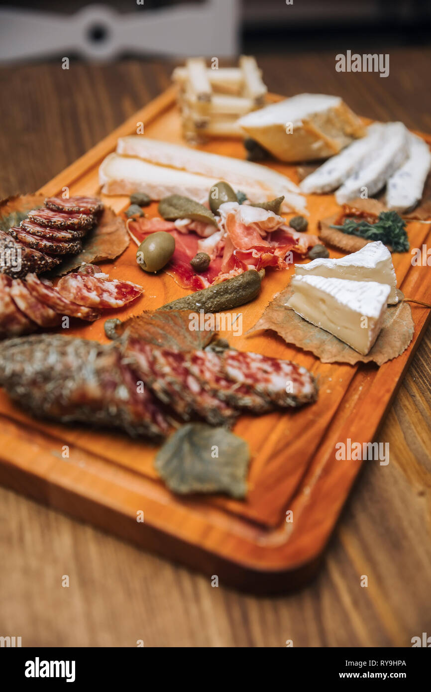 Käse und Wurst als Vorspeise auf hölzernen Platte serviert ...