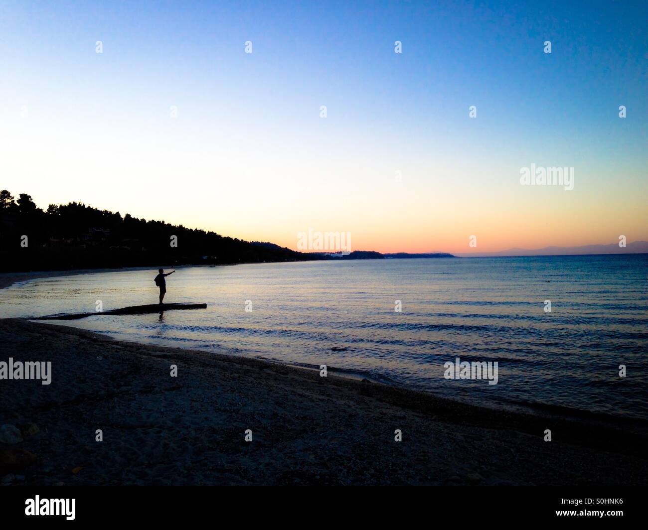 Mann am Steg Hinweisen zum Meer bei Sonnenuntergang über stilles Wasser ...