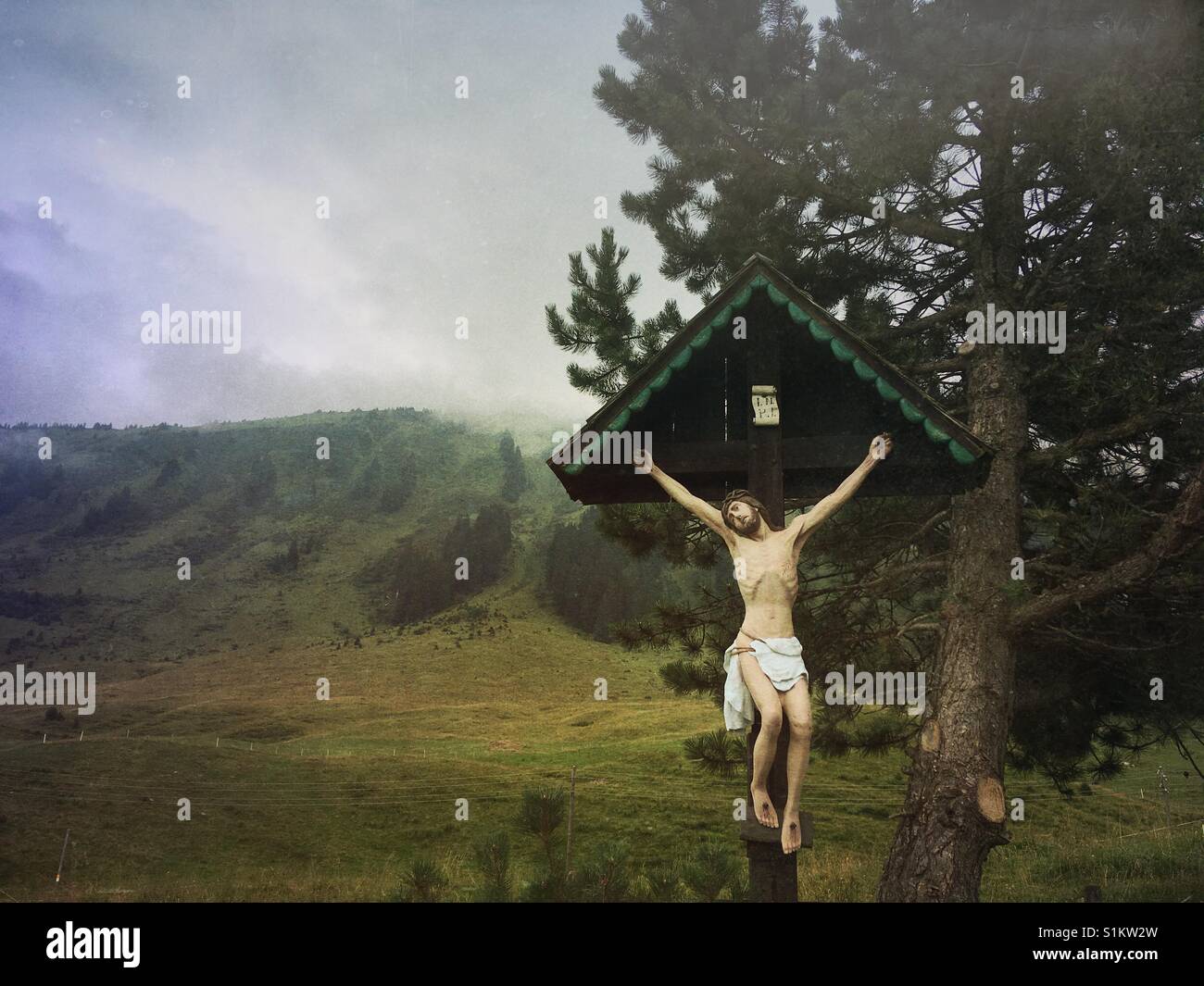 Eine Darstellung von Jesus Christus am Kreuz mit einem Berg und Wolken im Hintergrund ...