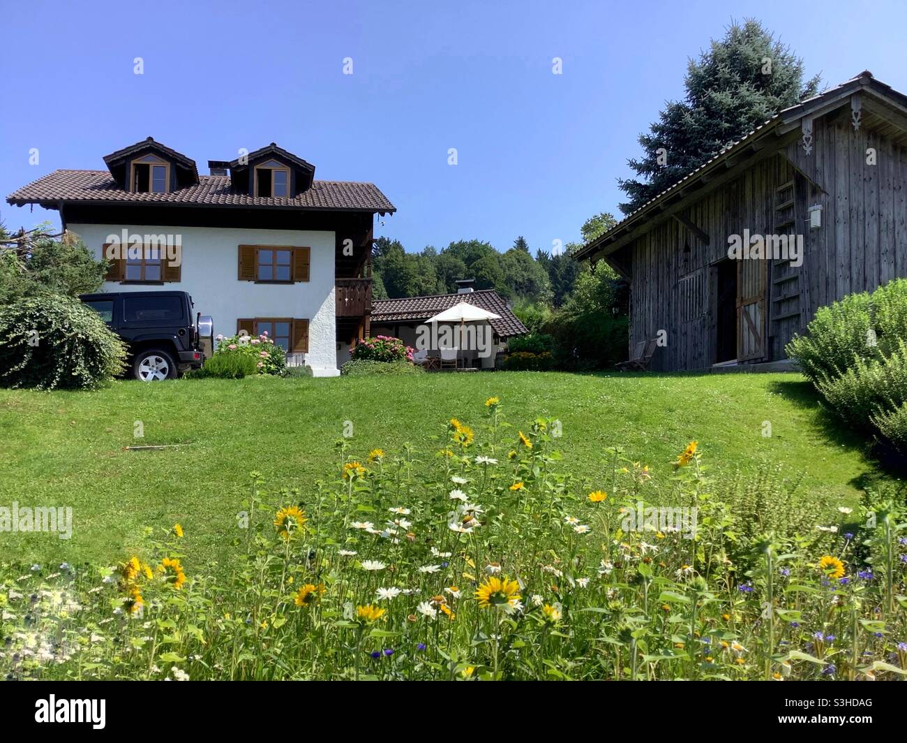 Altes bayerisches Bauernhaus mit Garten und blühenden Wildblumen im ...