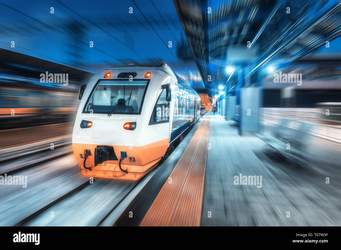 Fahrenden Zug auf dem Bahnhof in der Nacht. Städtische Landschaft mit ...