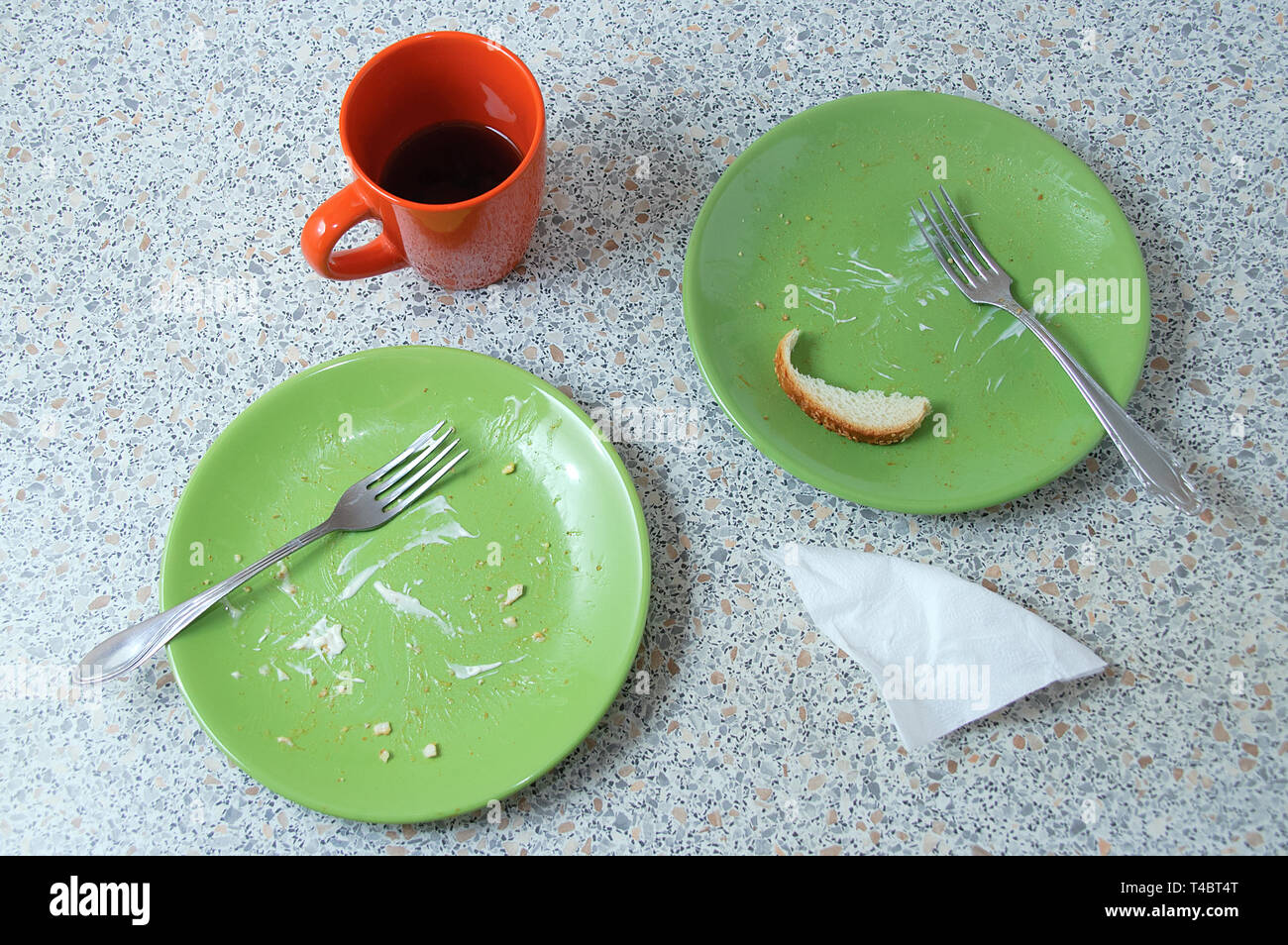 Grüne schmutzige Teller und eine Tasse mit den Resten der Küche. Auf ...