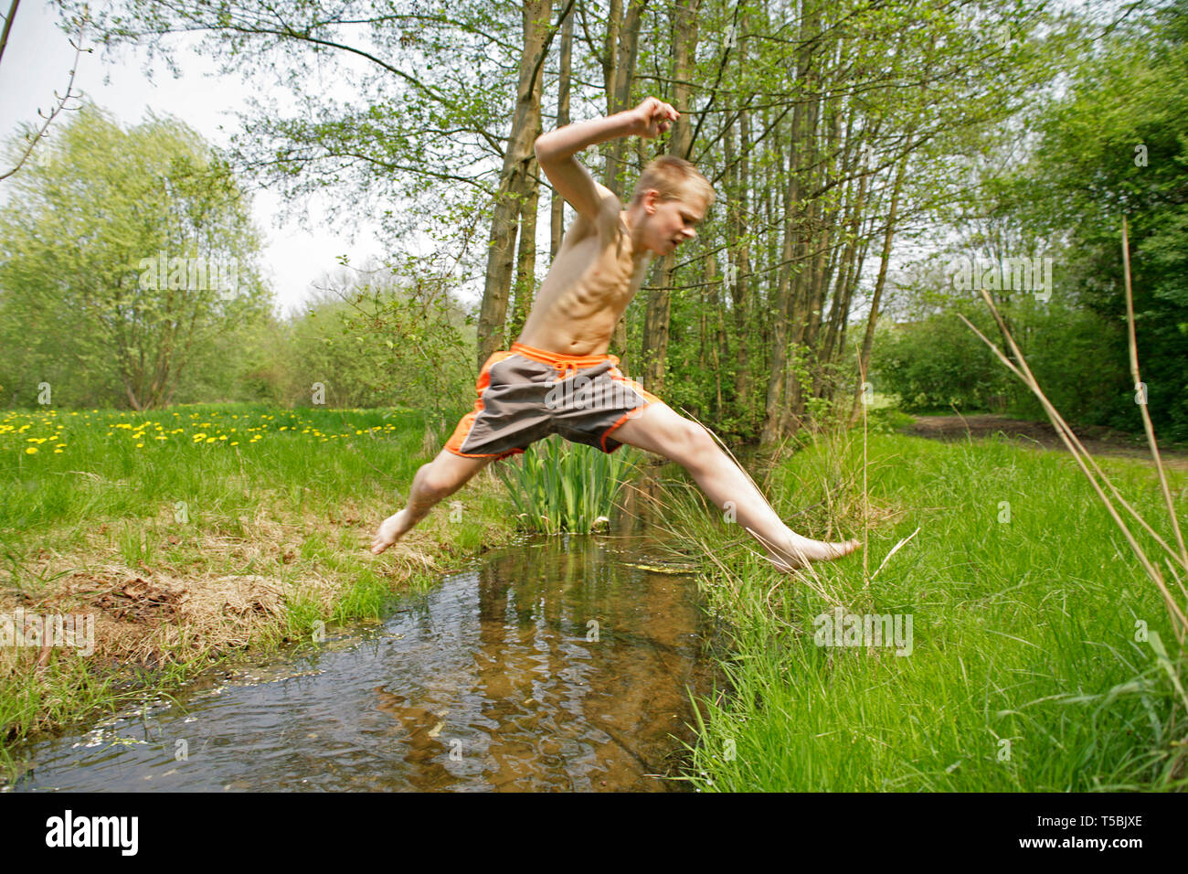 Teenager Jungen barfuß springen über einen Stream Stockfotografie - Alamy