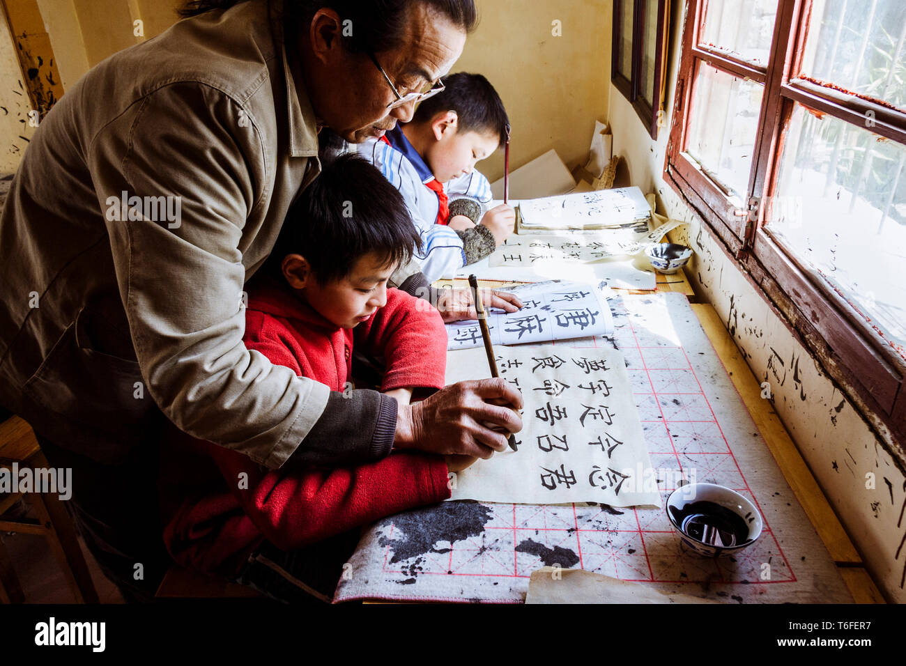 Lijiang, Yunnan, China: Ein chinesischer Kalligraphie Lehrerin hilft ... Lijiang, Yunnan, China: Ein chinesischer Kalligraphie Lehrerin hilft ...