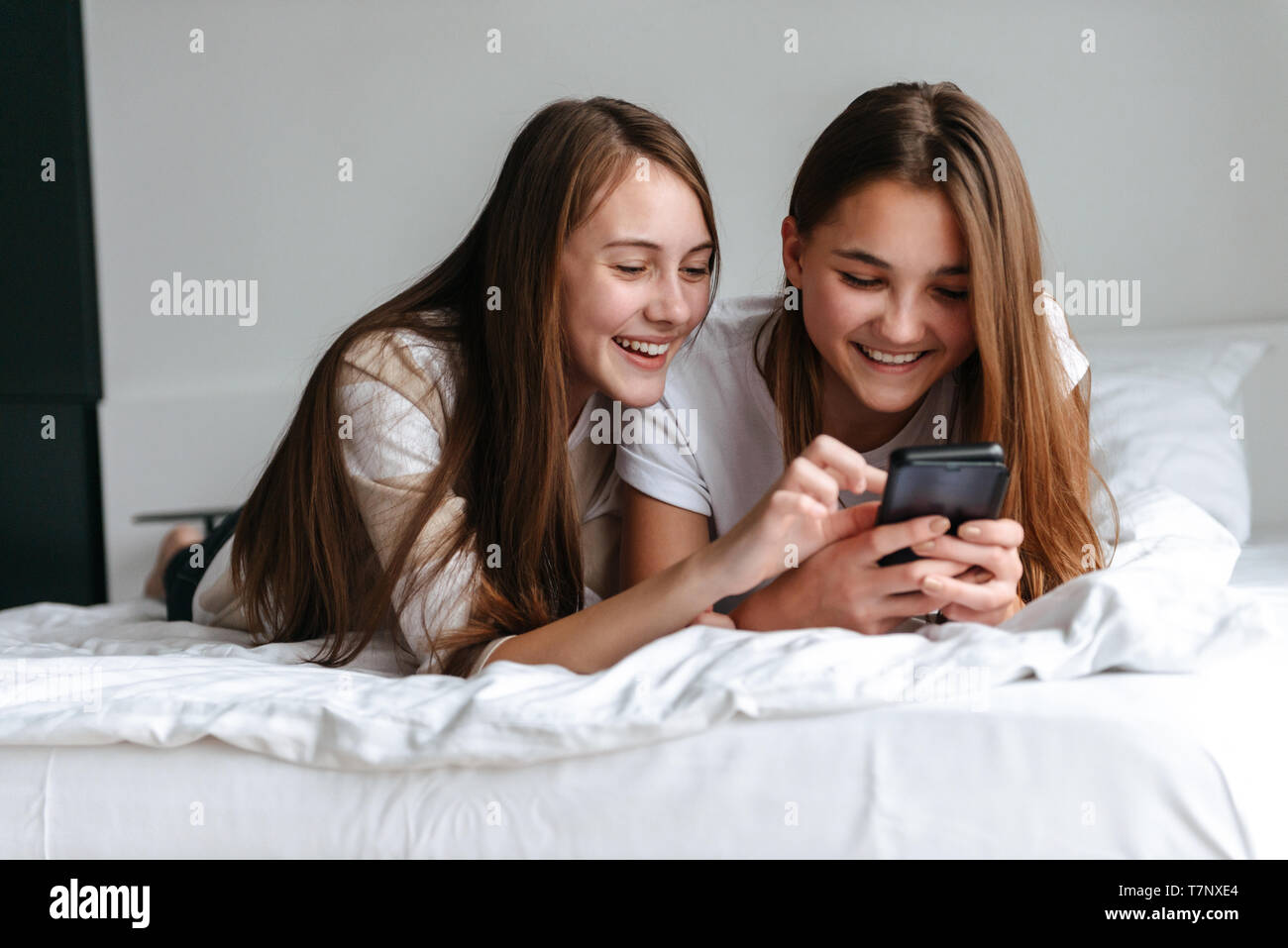 Zwei freundliche junge Mädchen im Teenageralter mit Handy bei der ... Zwei freundliche junge Mädchen im Teenageralter mit Handy bei der ...