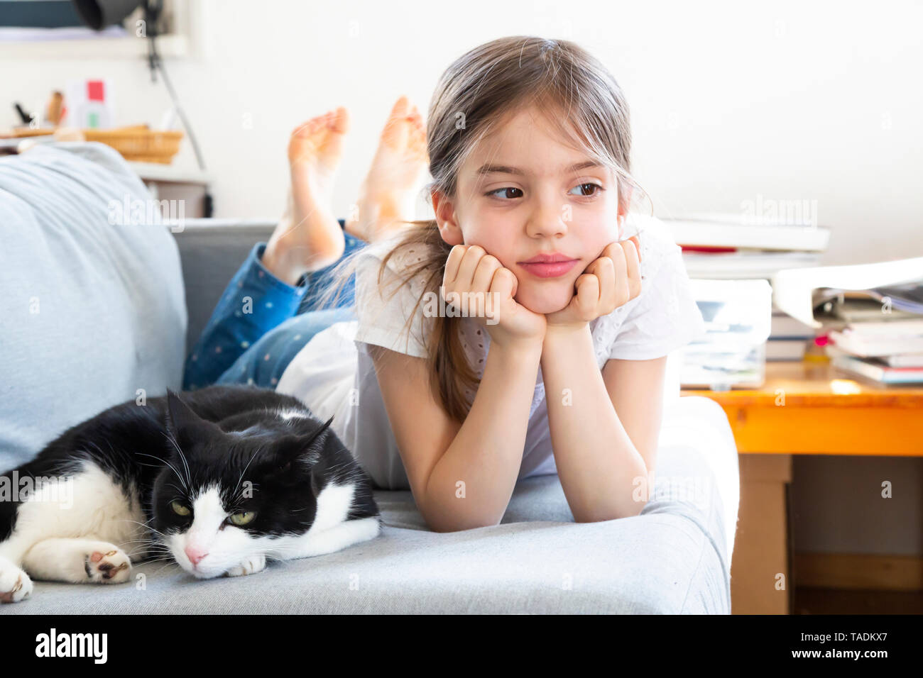 Porträt von kleinen Mädchen auf der Couch liegend mit Katze ...