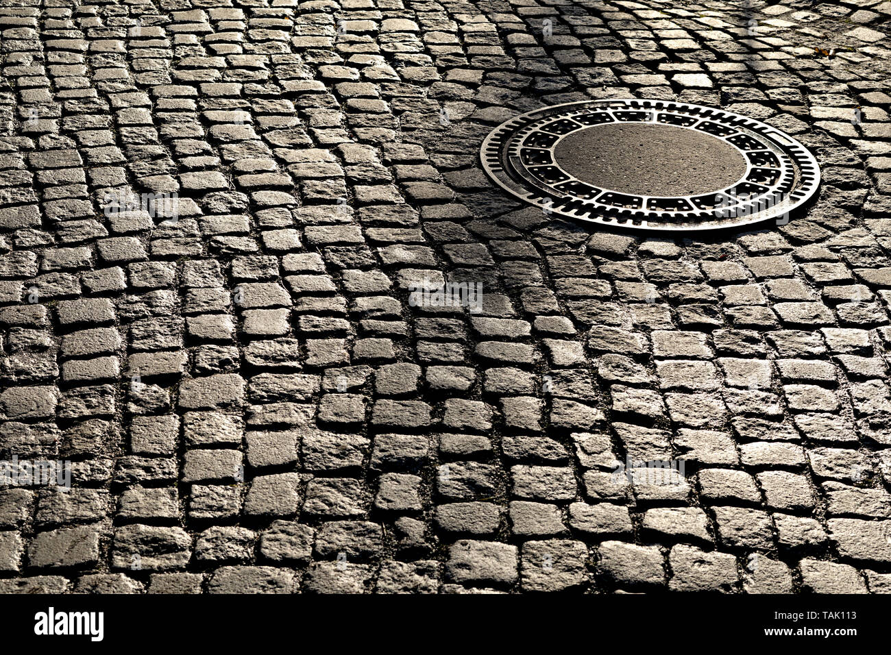 Kanaldeckel auf einer Straße mit Kopfsteinpflaster Stockfotografie - Alamy