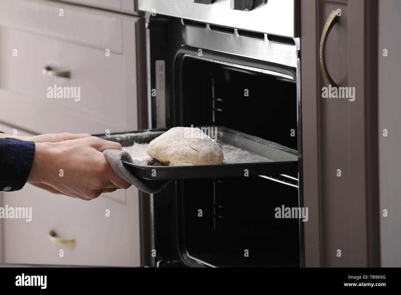 Frau putting Backblech mit rohen Teig für Brot in den Backofen ...