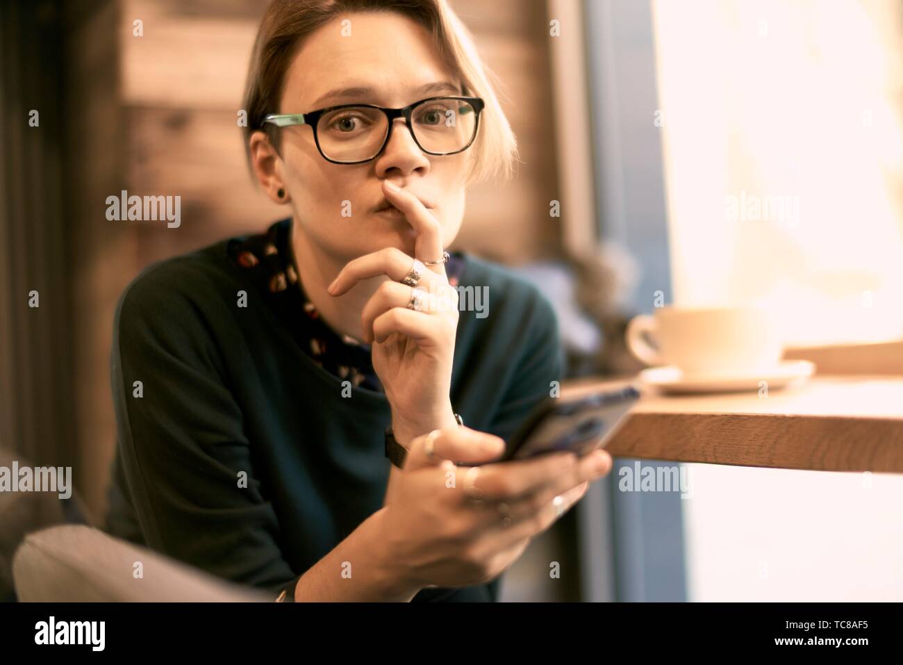 Diskrete Frau mit Smartphone drinnen im Café, Pause, München ...