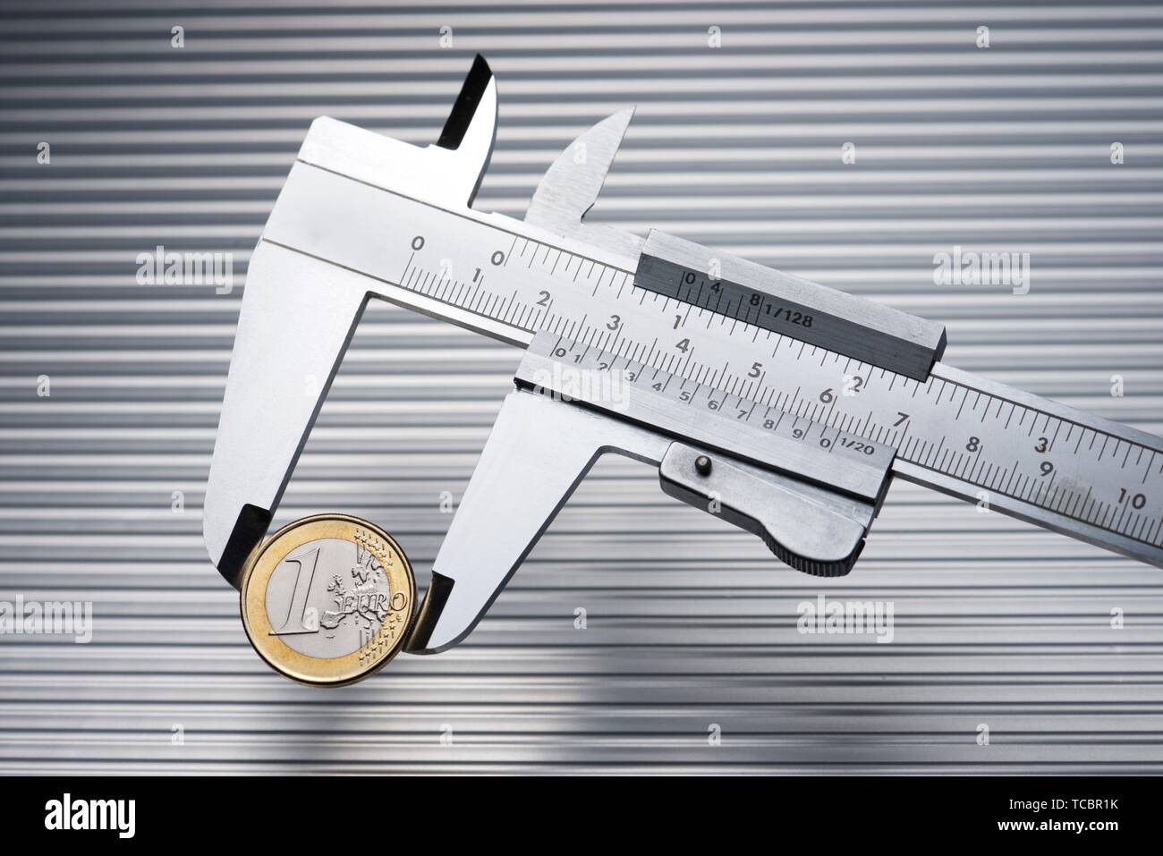 Blechlehre messen einer 1 Euro Münze auf einer Metalloberfläche ...