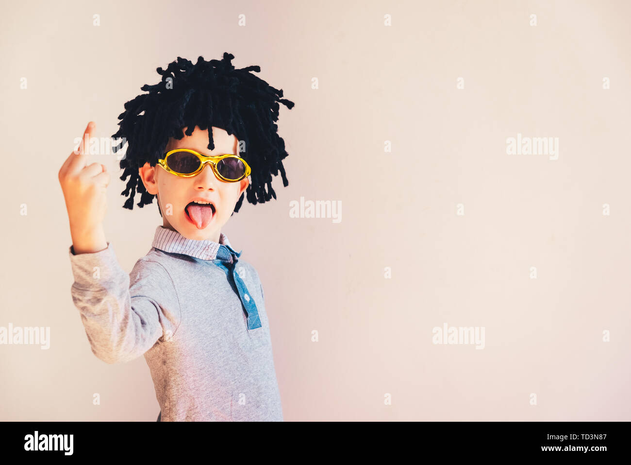 Kind gekleidet in lustige Perücke zeigt Mittelfinger zu lachen ...