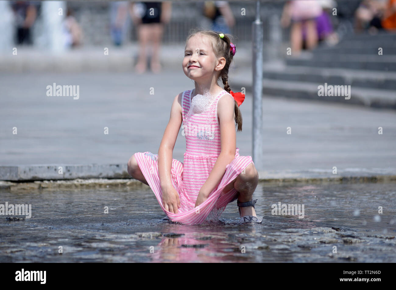 Starke Hitze in der Stadt: Mädchen spielen mit Springbrunnen ...