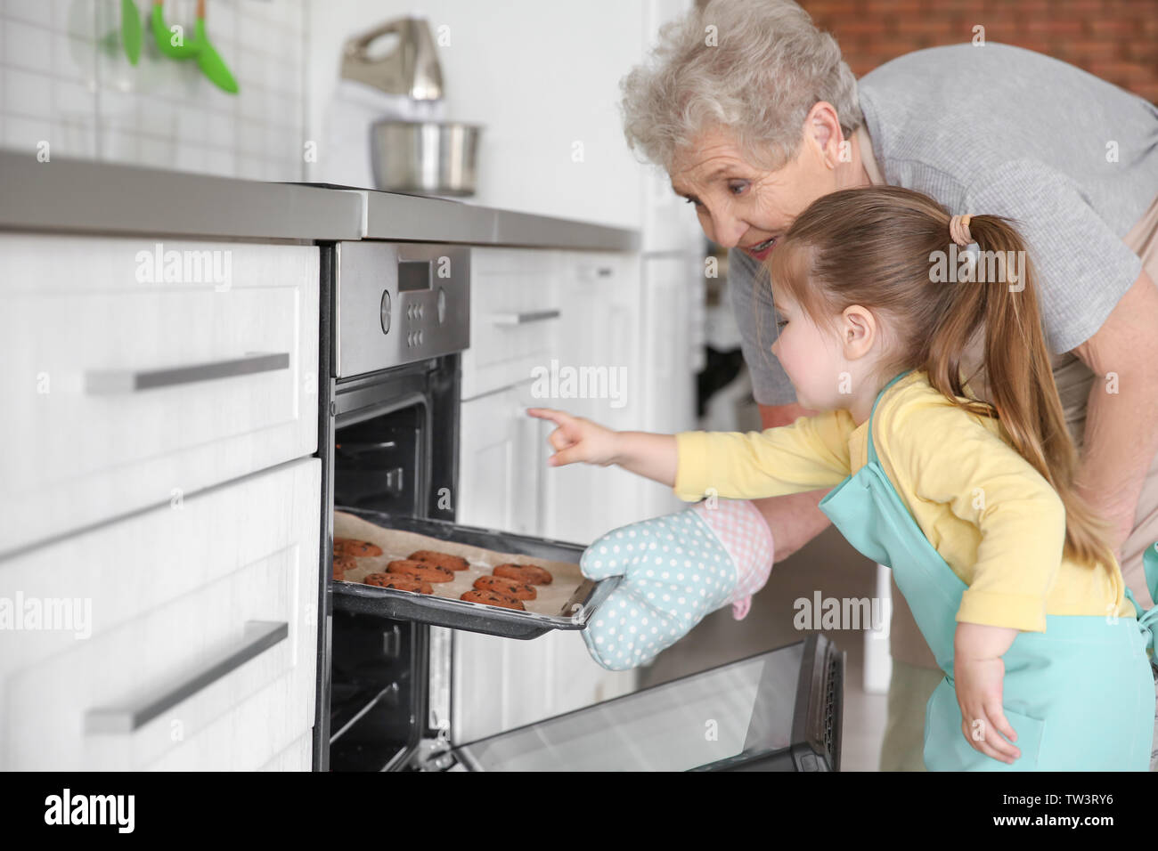 Süße kleine Mädchen und ihre Großmutter die Cookies aus dem Ofen auf ... Süße kleine Mädchen und ihre Großmutter die Cookies aus dem Ofen auf ...