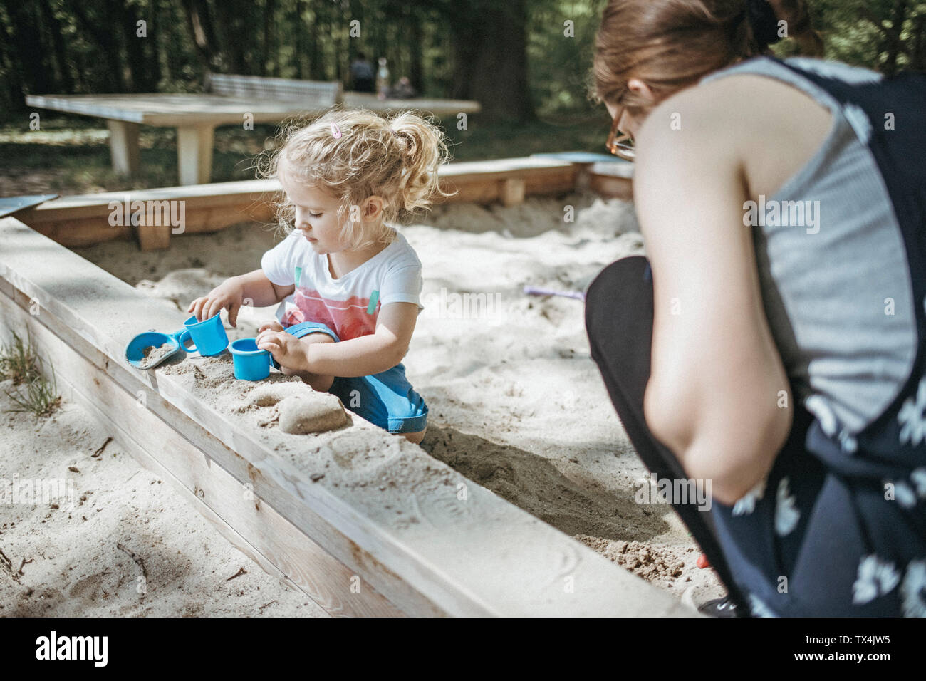 Mutter spielt mit kleiner Tochter in den Sandkasten auf dem Spielplatz ...