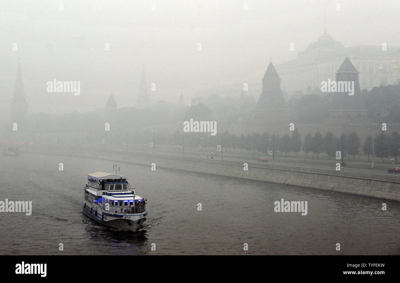 Ein Boot fährt auf der Moskwa entlang der Kreml durch eine schwere Smog ...