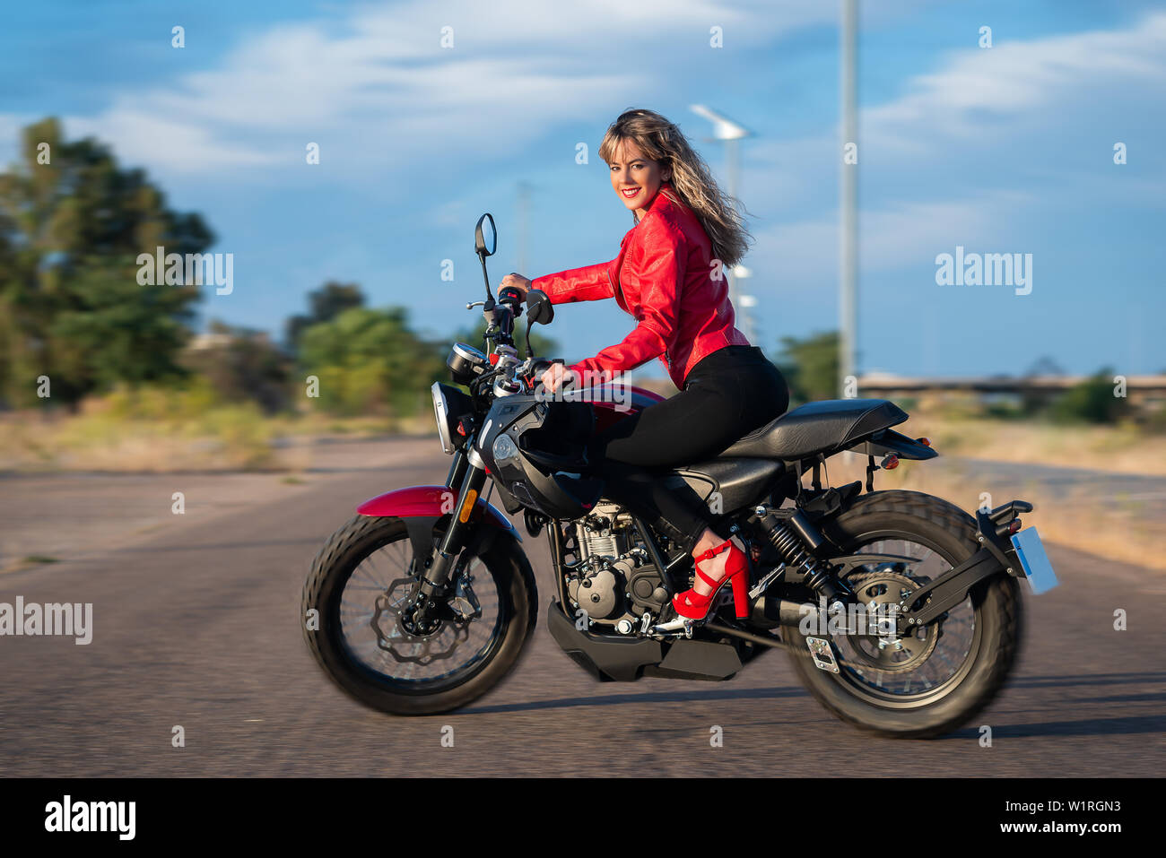 Glückliche junge Frau, die auf einem roten Motorrad Stockfotografie - Alamy
