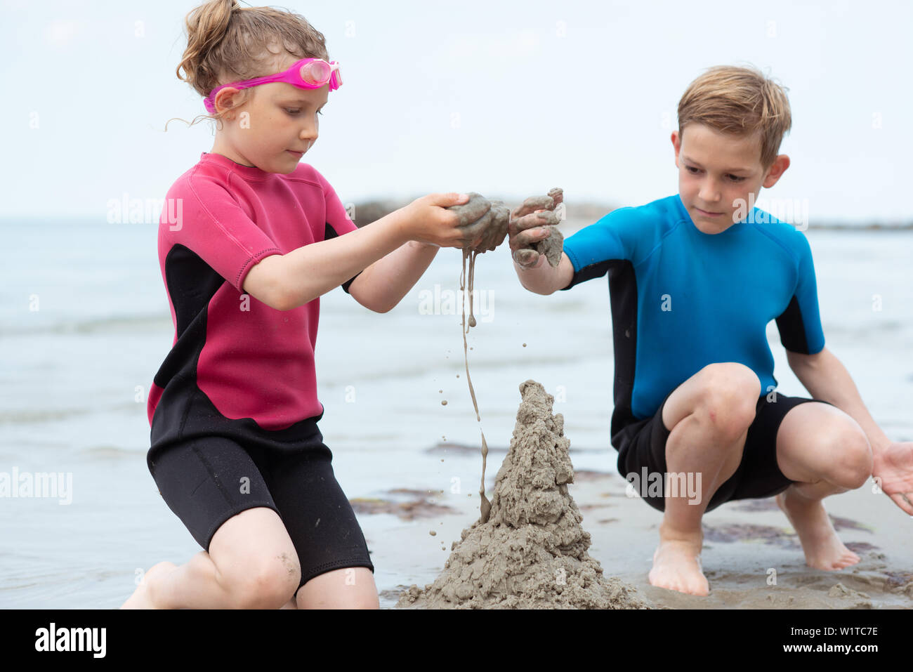 Zwei glückliche Geschwister Kinder in Neopren schwimmanzüge Spielen mit ...