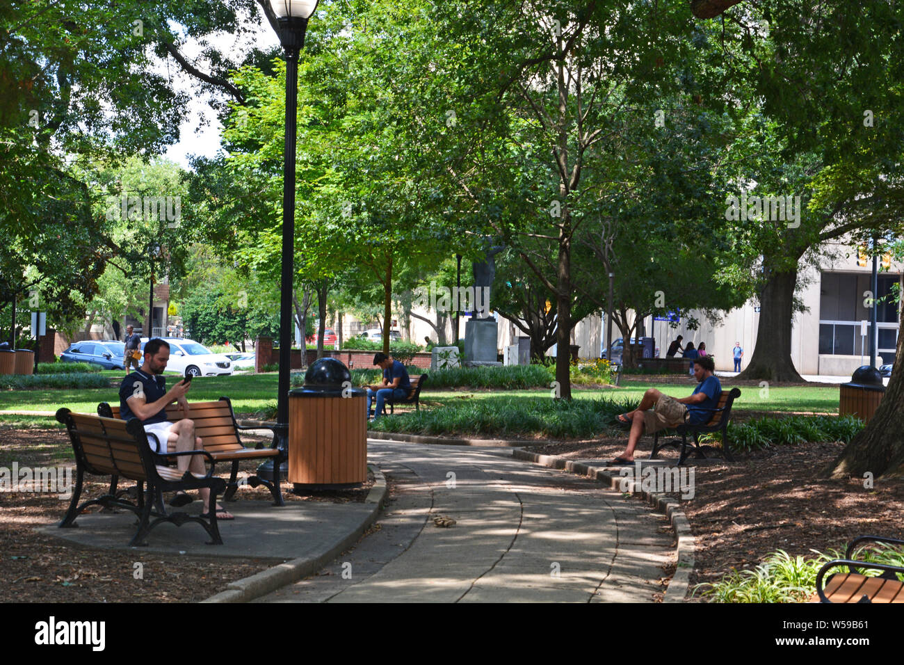 Besucher sitzen im Park und sind auf Ihre Telefone an Nash Square in ...