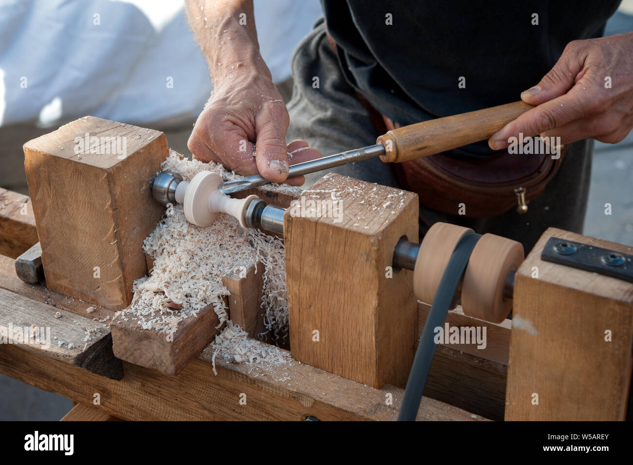Ein Handwerker schnitzt ein Stück Holz mit einer manuellen Drehmaschine ...