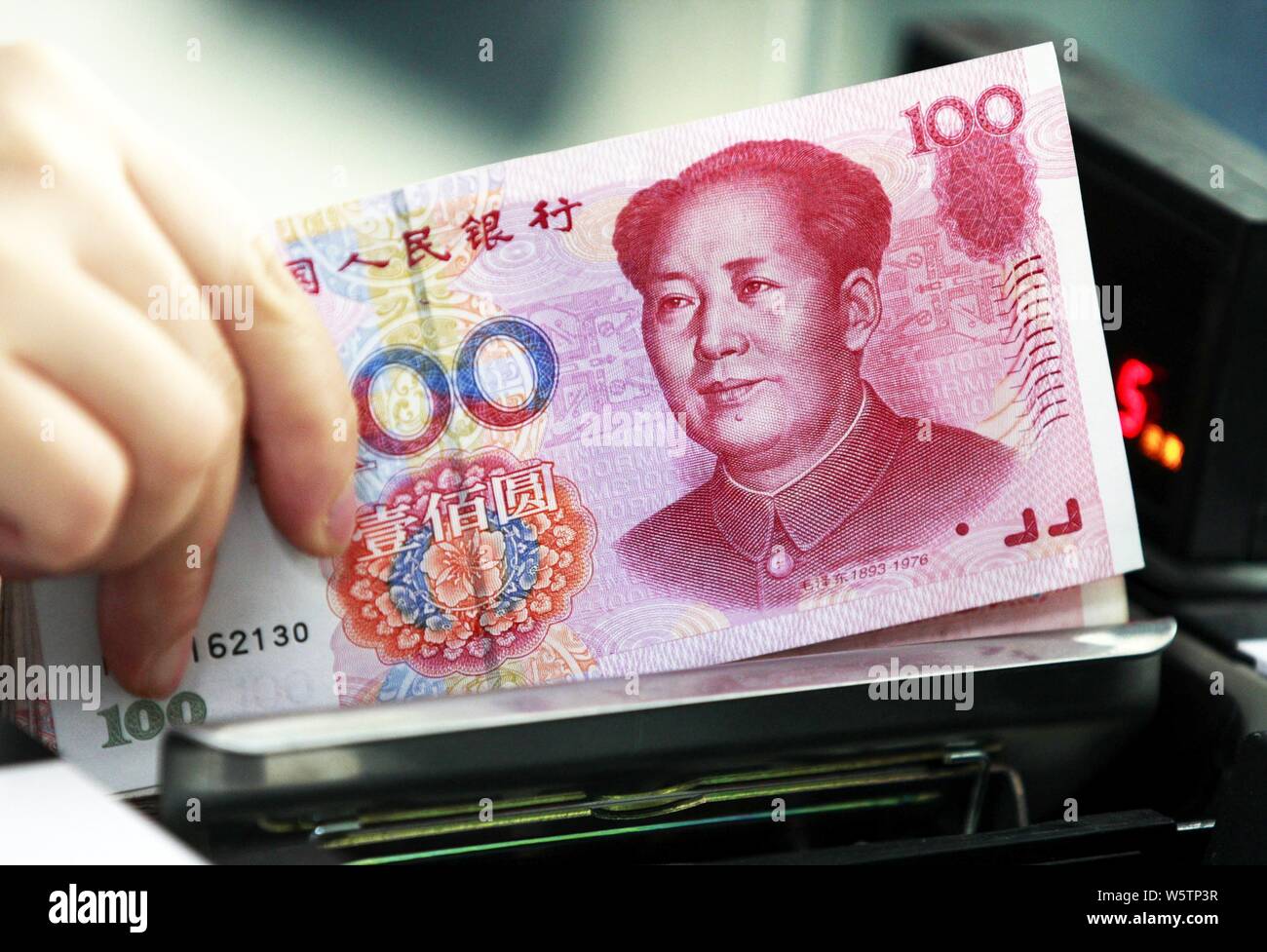 Eine chinesische Angestellte zählt RMB (Renminbi) Yuan Banknoten bei ...