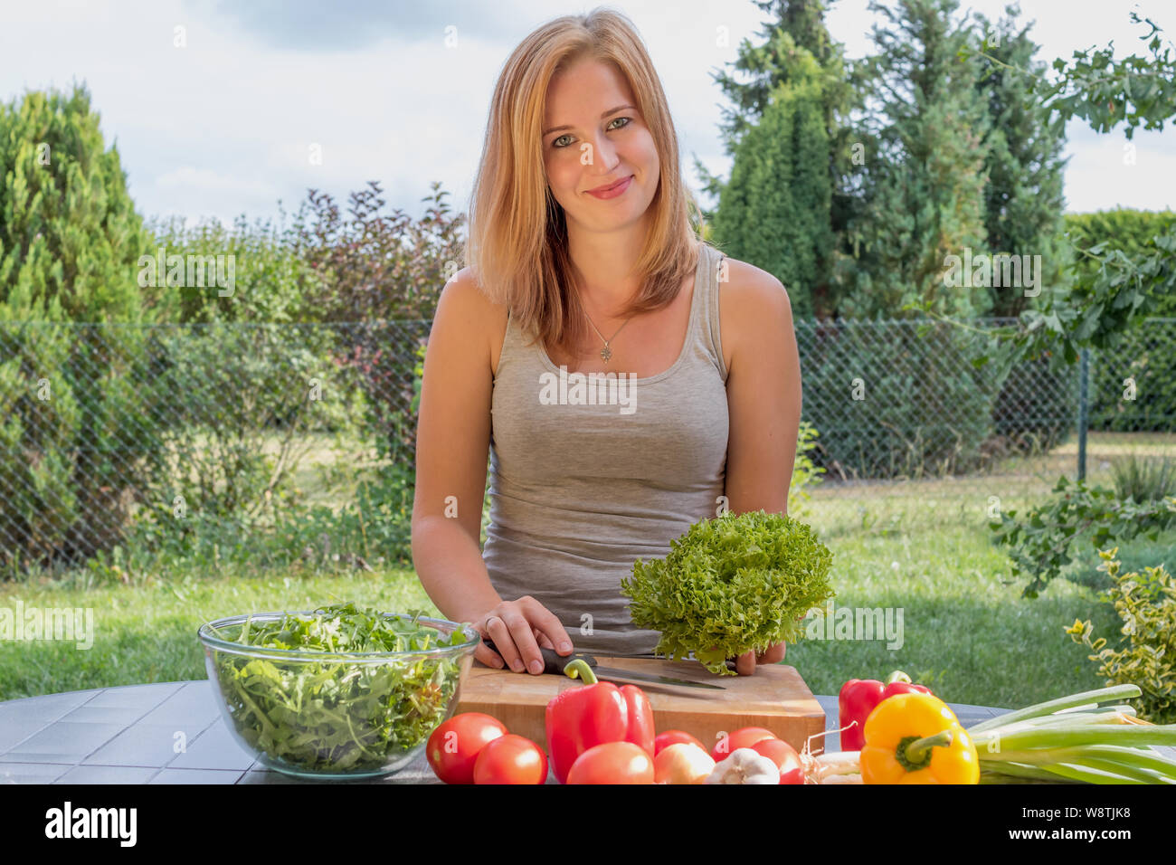 Schöne junge Frau bereitet Gemüse essen im Freien. Sie hält eine Leiter der grünen Salat in die ...